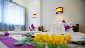 Quarto de hotel com cama bem arrumada, mesa de cabeceira e luminária fixada na parede.