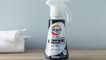 Uma embalagem de Attack Zero, detergente de lavagem, sobre uma superfície de madeira, com uma toalha branca dobrada ao fundo.