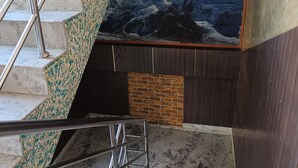 Uma escadaria com corrimão de metal, um mural com cena de montanha e uma parede de tijolos.