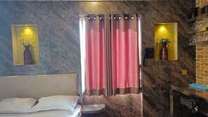 Quarto com cama, cortina de chuveiro, penteadeira com espelho e uma mesinha.