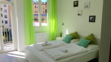 Quarto com duas camas, varanda e vista para edifícios.