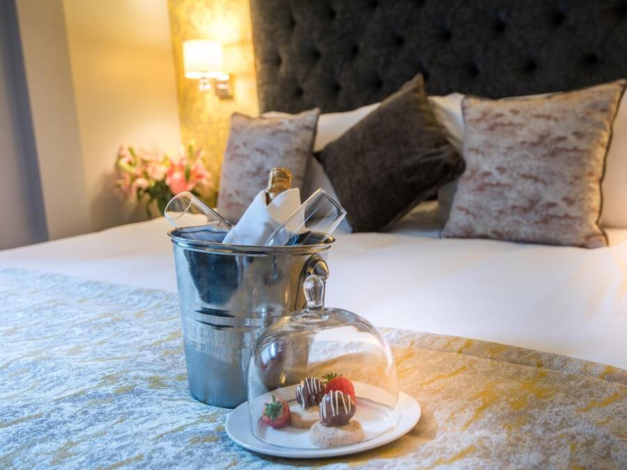 Uma cama com um balde de metal contendo copos e um prato de comida.