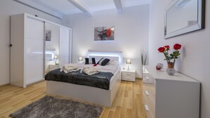 Quarto moderno com cama, mesas de cabeceira, guarda-roupa e espelho.