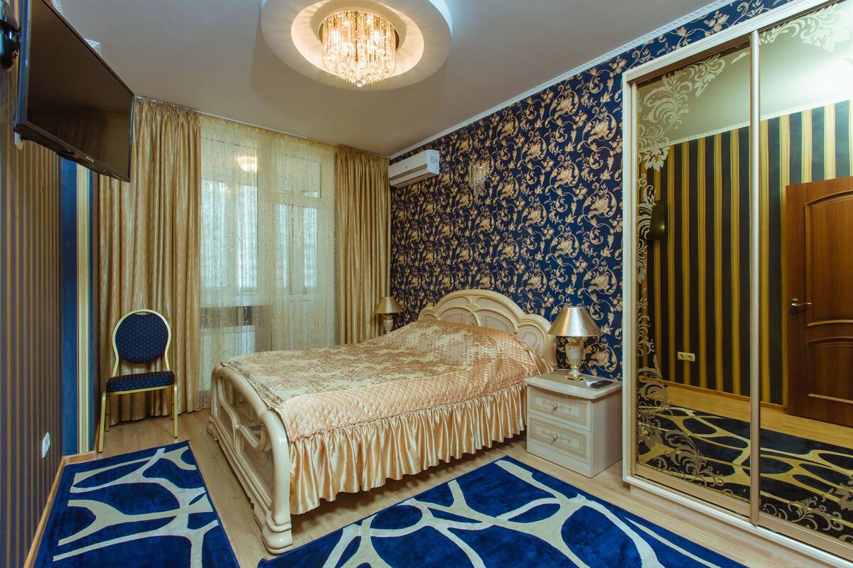Quarto com cama, cadeira, mesa de cabeceira, ar condicionado e guarda-roupa.