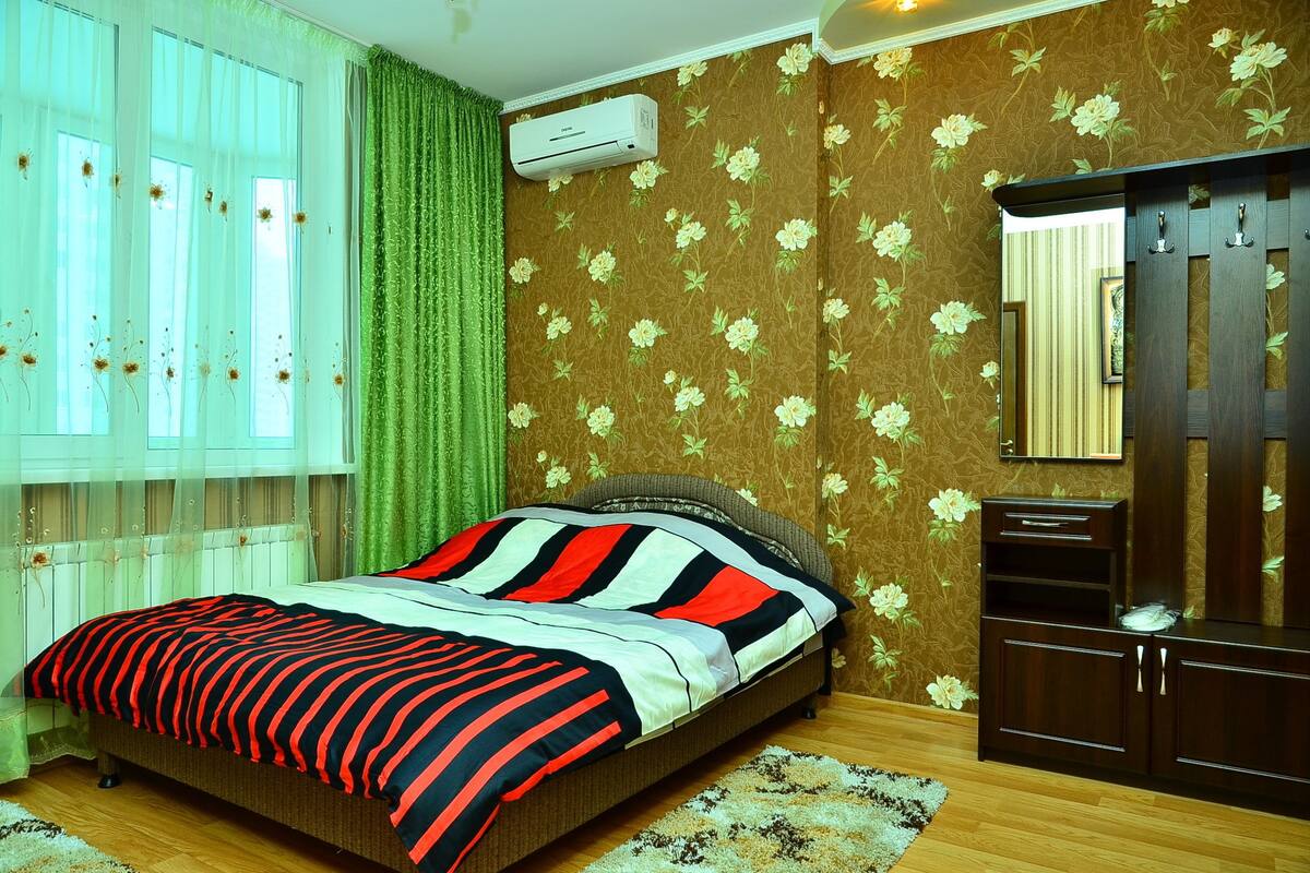 Um quarto com uma cama, cômoda, espelho e radiador.