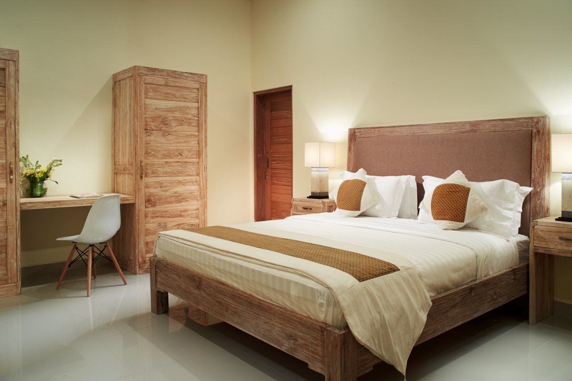 Um quarto com cama de madeira, escrivaninha e cadeira.