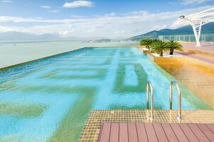 Uma piscina com água azul cristalina, um deck de madeira e uma estrutura branca com telhado.