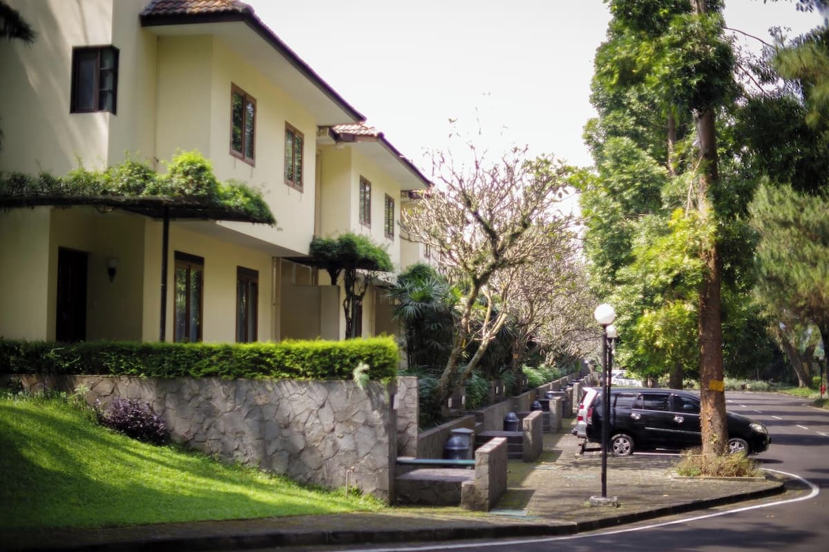 Um edifício residencial com muro de pedra, calçada pavimentada e um carro estacionado.