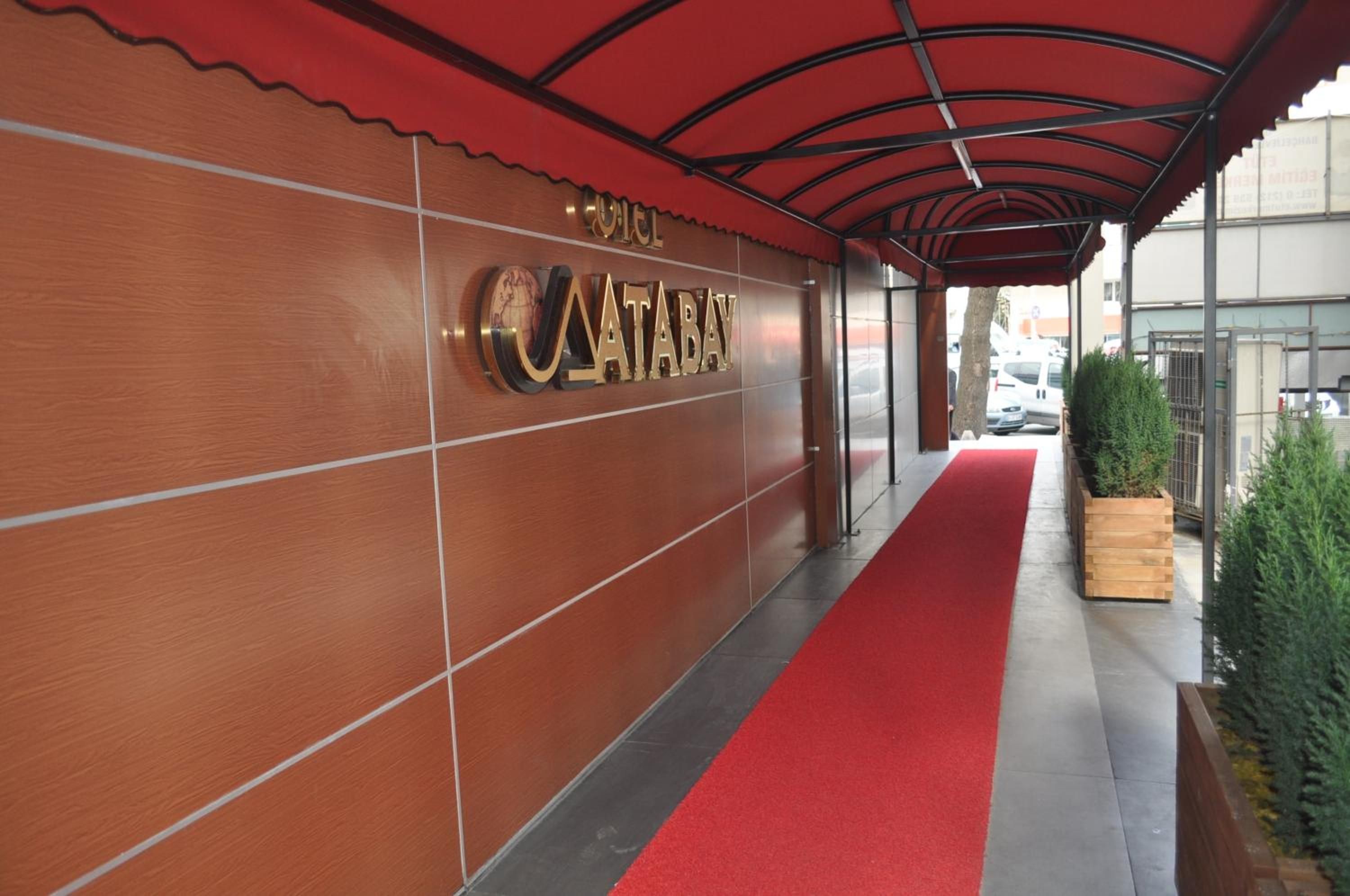 Entrada de hotel com tapete vermelho que leva a uma área coberta.