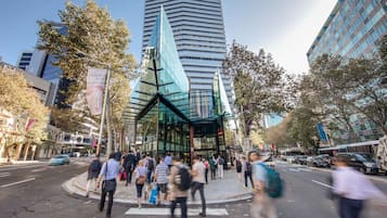 Um edifício moderno com fachada de vidro e uma estrutura triangular singular à frente.