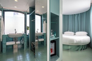Casa de banho moderna com duas pias, cabine de duche em vidro e mini-frigorífico embutido.