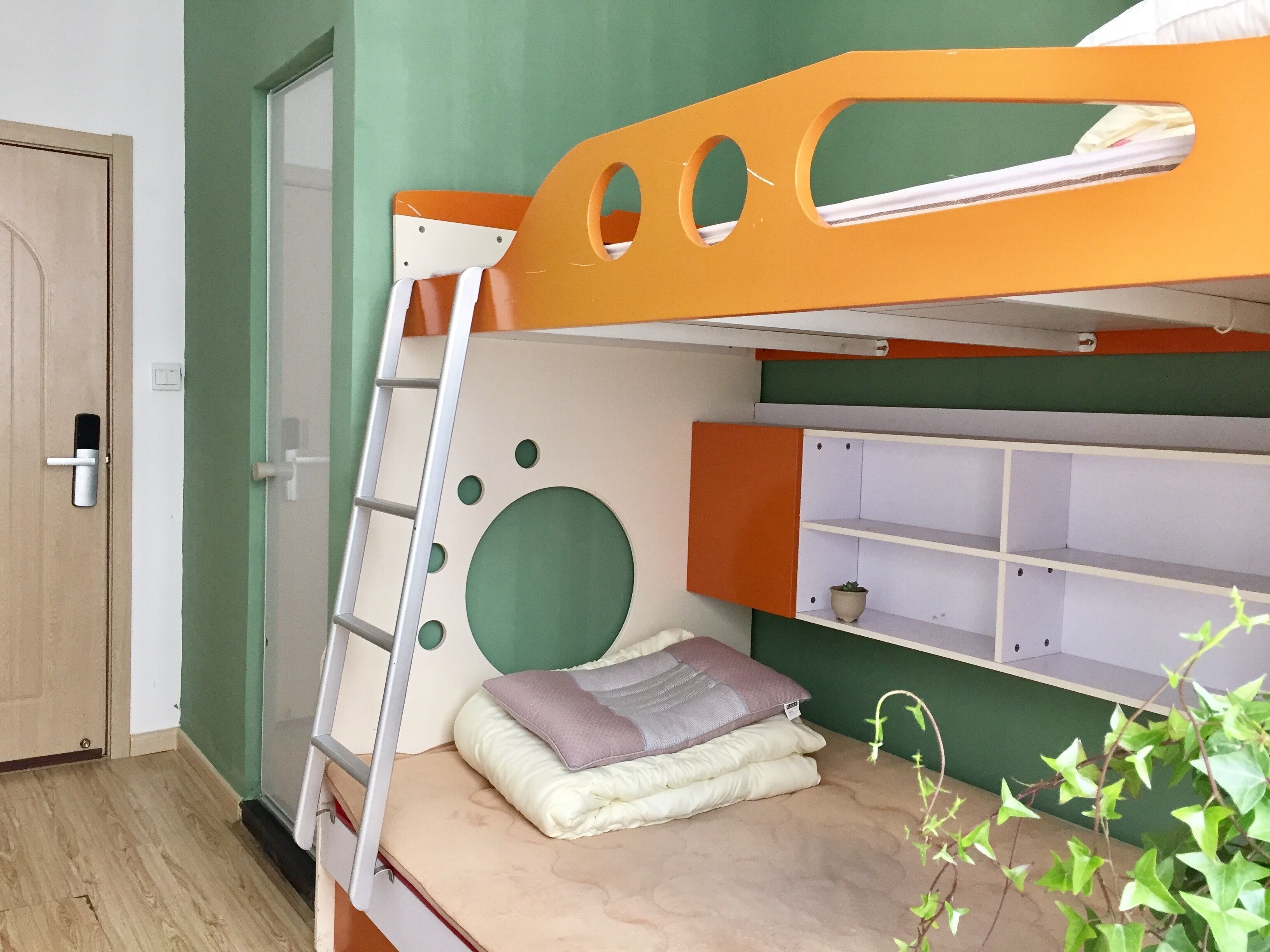 Uma cama beliche com escada, mesa de cabeceira, prateleira e porta.