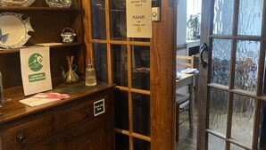 Interior de madeira com um kit de primeiros socorros, um aviso solicitando álcool em gel e uma porta com sinal de alerta.