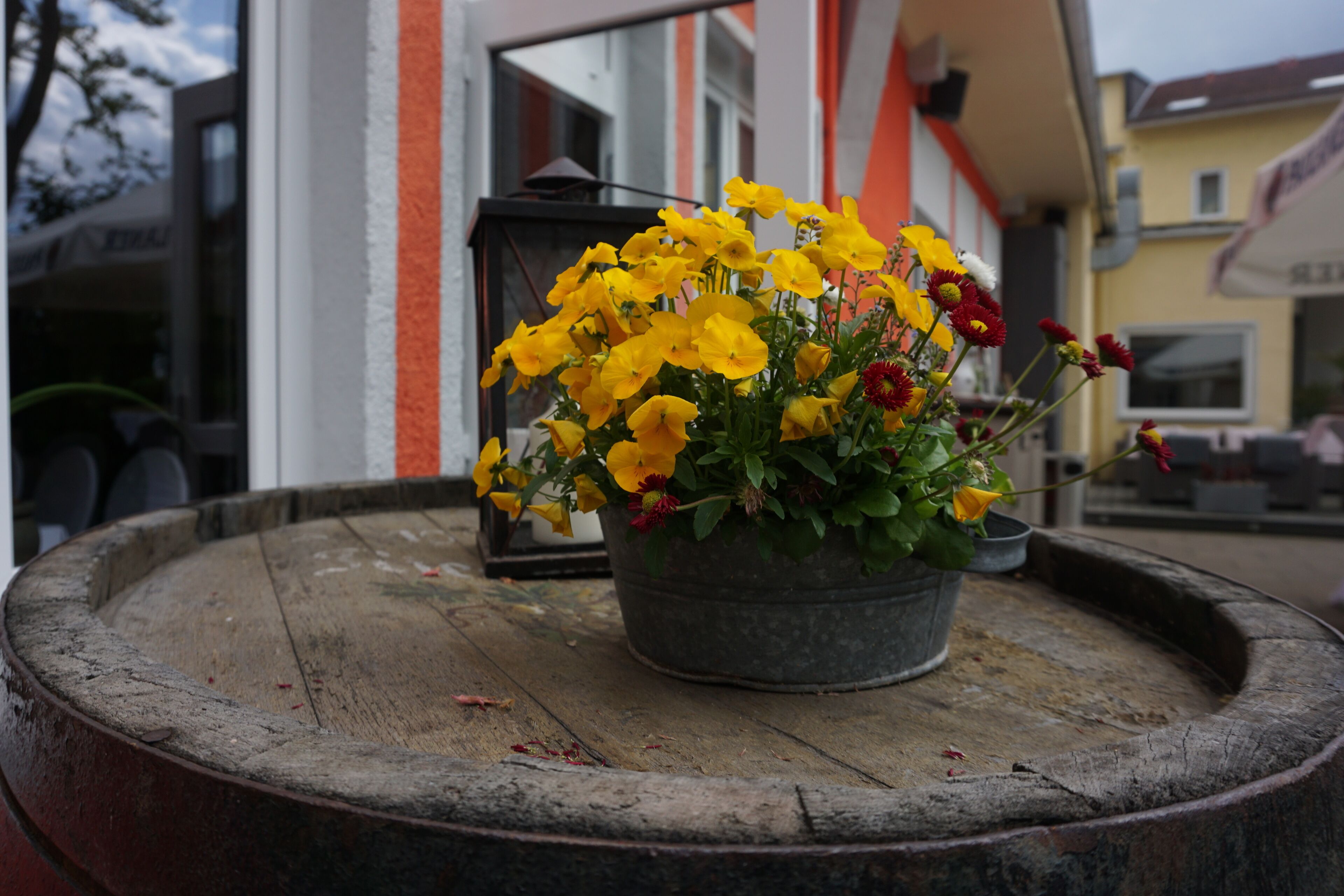 Um arranjo de flores amarelas em vaso sobre um barril de madeira.