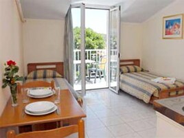 Um quarto com uma cama, uma mesa de jantar com cadeiras e uma varanda com mesa e cadeiras.