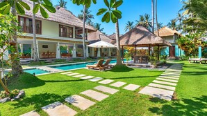 Um resort tropical com piscina, construções de palha e vegetação exuberante.