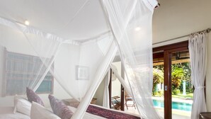 Quarto com cama, roupa de cama branca, dossel e vista para uma piscina.
