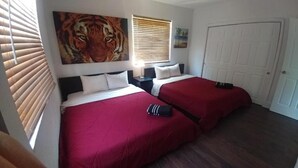 Quarto com duas camas, um quadro de tigre e uma porta.