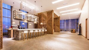 Uma área de bar moderna com ilha central, banquetas, iluminação pendente e parede estampada.