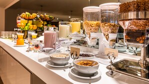 Buffet com diversas opções de alimentos, incluindo cereais, frutas e bebidas.