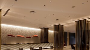 Um hall espaçoso com design moderno, destacando uma parede texturizada, um espaço de estar e um balcão de recepção.