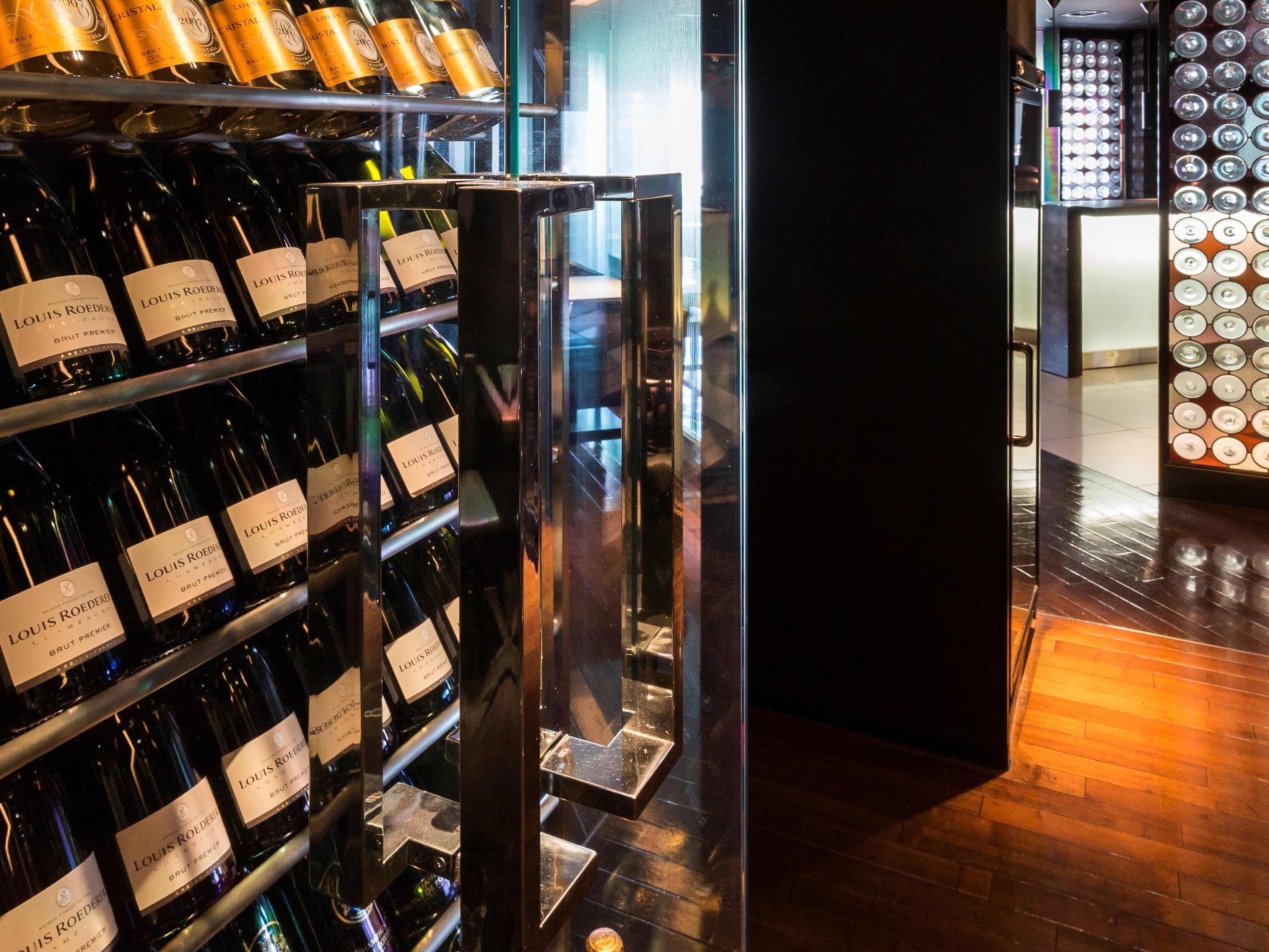 Exposição de vinhos com garrafas rotuladas 'Louis Roederer Brut Premier' em uma loja moderna e bem iluminada.