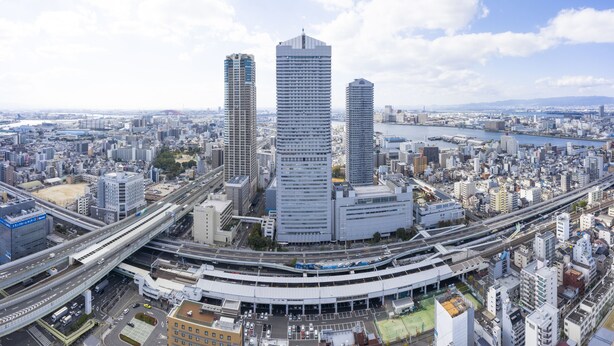 Uma área urbana com edifícios altos e arquitetura moderna, incluindo um edifício com design marcante e uma estrutura circular com teto.