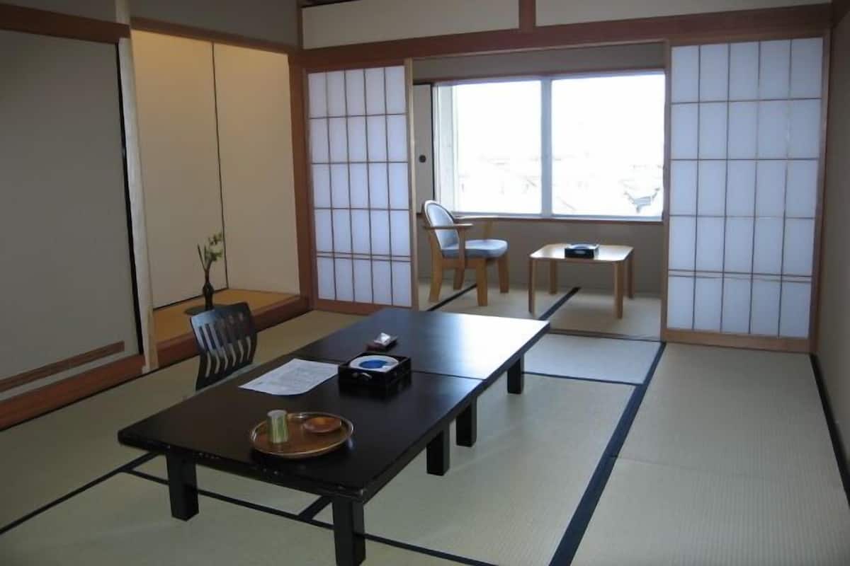 Um quarto japonês tradicional com tatames, uma mesa baixa com uma bandeja e uma porta deslizante.