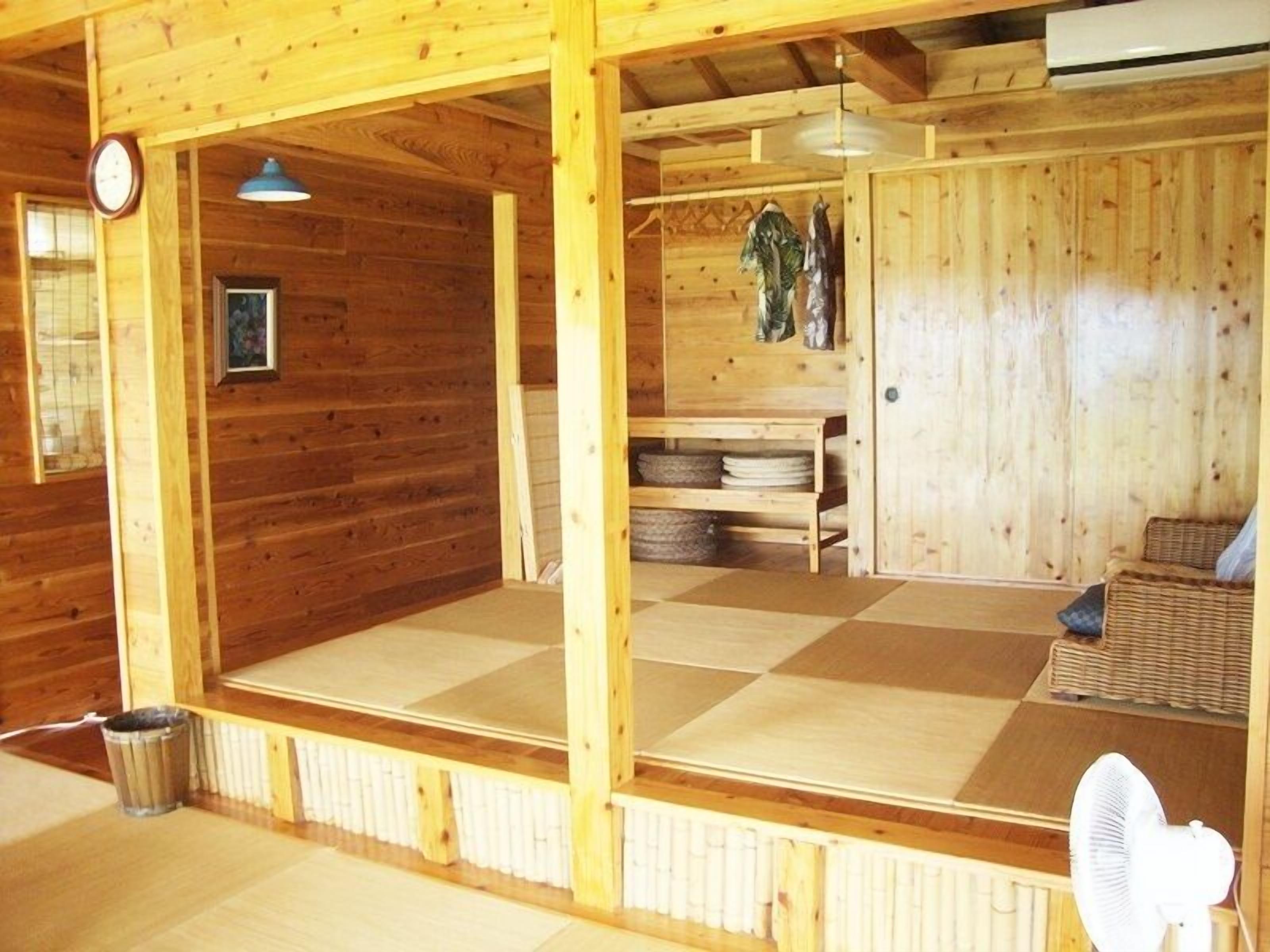 Um interior de madeira com piso xadrez, um ventilador e um relógio.
