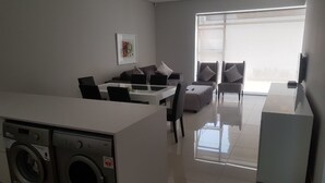 Uma sala de estar moderna com sofá, mesa de jantar e uma janela grande.