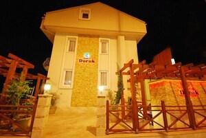 Um hotel chamado 'Hotel Doruk' com fachada de pedra, portão de entrada de madeira e um letreiro acima da porta.