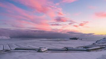 Paisagem coberta de neve com um conjunto de edifícios e um vasto campo aberto.