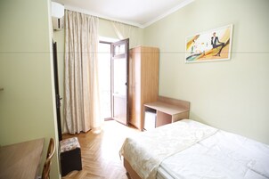 Quarto com cama, escrivaninha, guarda-roupa e um quadro na parede.