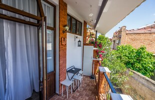 Uma varanda com mesa e cadeiras, uma planta pendente e um muro de tijolos.