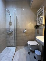 Um banheiro moderno com box de vidro, vaso sanitário e pia.