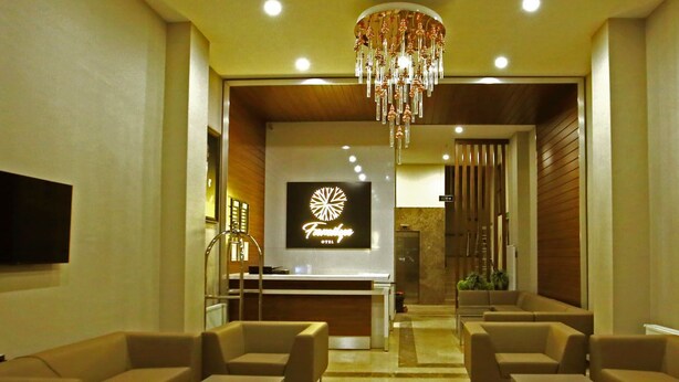 Um hall de hotel com balcão de recepção, área de estar e um lustre.