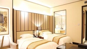 Quarto de hotel com duas camas, uma escrivaninha, uma cadeira e um espelho grande.