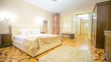 Quarto com uma cama grande, um candelabro, piso estampado e um guarda-roupa de madeira.