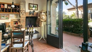 Um quarto aconchegante com lareira, uma mesa de jantar com cadeiras, uma estante de livros e um amplo painel de vidro deslizante que dá para uma área externa.