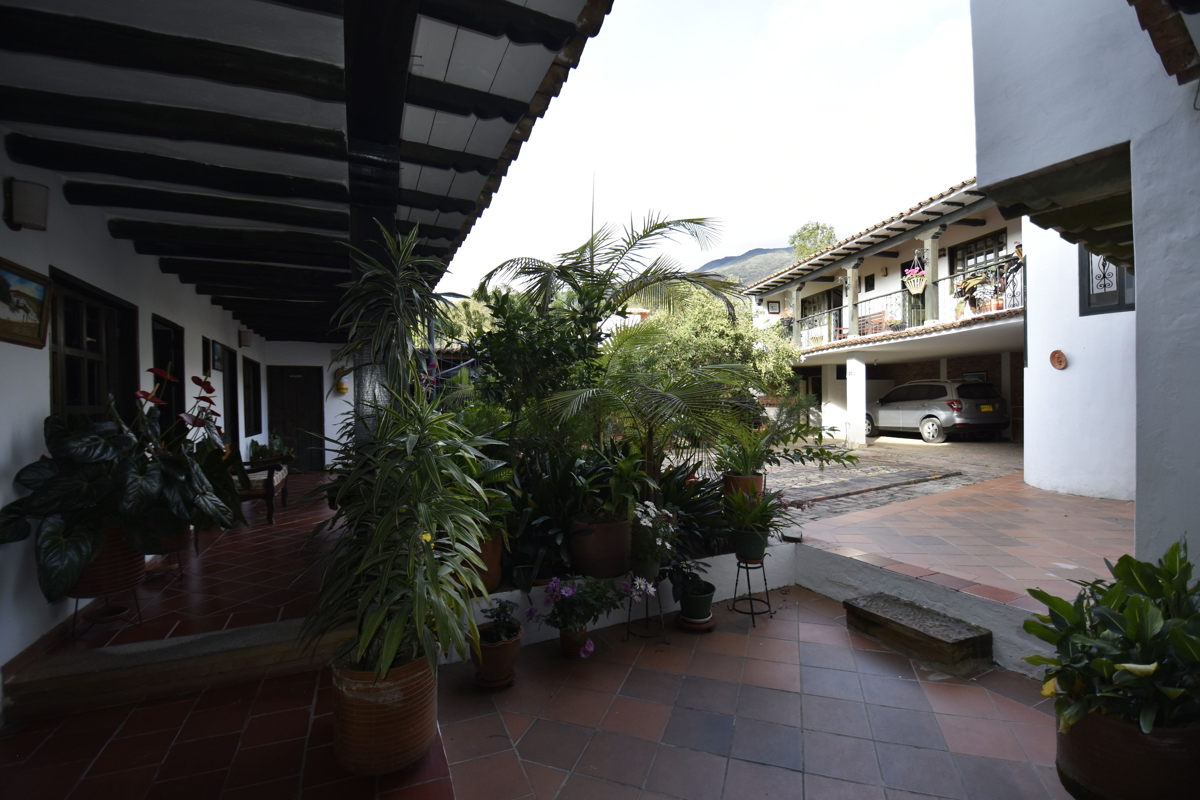 Um pátio com plantas em vasos, piso de azulejos e um edifício com varandas.
