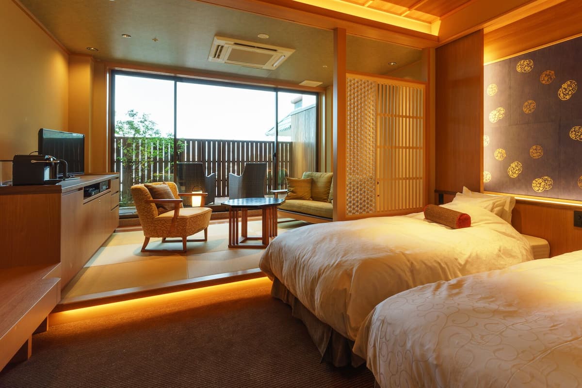 Quarto de hotel com duas camas, um espaço para refeições e vista para o exterior.