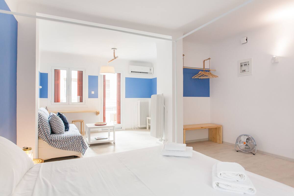 Quarto de hotel moderno com cama, mesa de cabeceira, poltrona, escrivaninha, cabideiro e radiador.