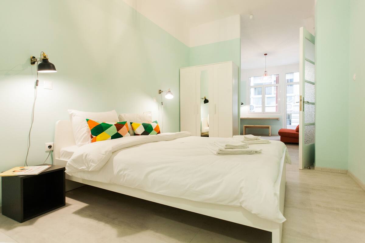 Quarto moderno com cama, luminárias de cabeceira, mesa de cabeceira e guarda-roupa.