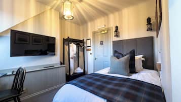 Quarto de hotel com uma cama, uma escrivaninha, uma cadeira, um guarda-roupa e um espelho.