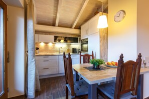 Uma cozinha moderna com armários brancos, uma mesa de jantar de madeira e um relógio na parede.