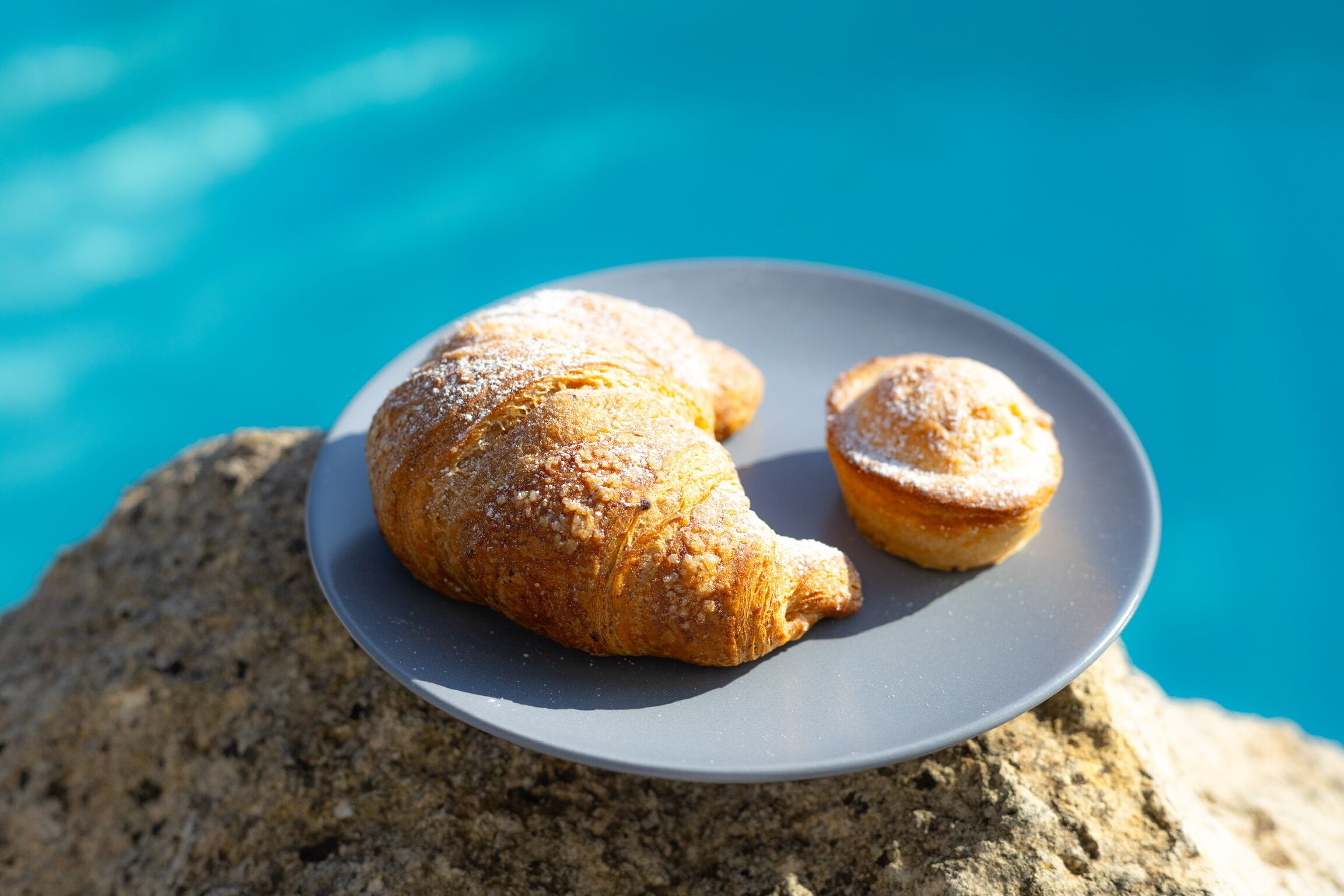 Um prato com dois doces sobre uma rocha, perto de uma piscina.