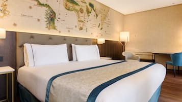 Quarto de hotel com uma cama grande, uma escrivaninha e uma cadeira.