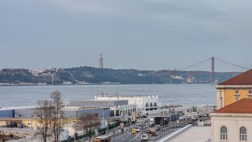 Paisagem urbana com uma ponte imponente, uma orla movimentada e uma rua cheia de carros e pedestres.