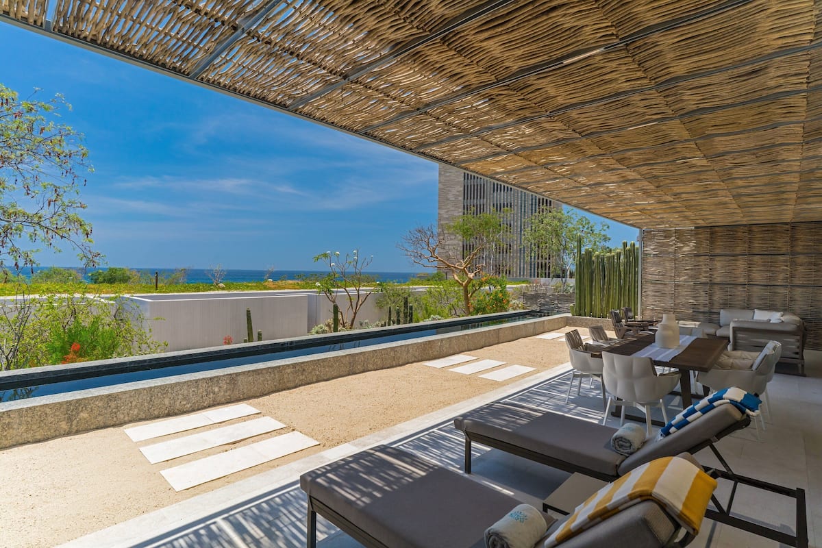 Uma área de estar moderna ao ar livre, com piscina, assentos e vista para o oceano.