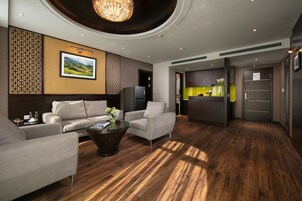 Um hall de hotel moderno com piso de madeira, um sofá, uma mesa de centro e um quadro na parede.
